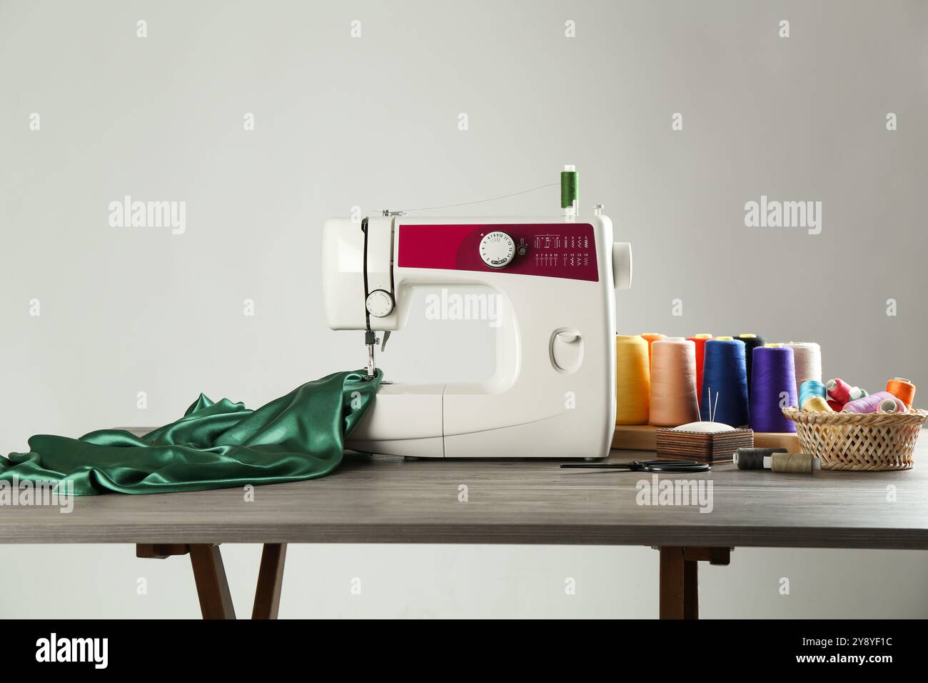 Sewing machine, green fabric and craft accessories on wooden table ...