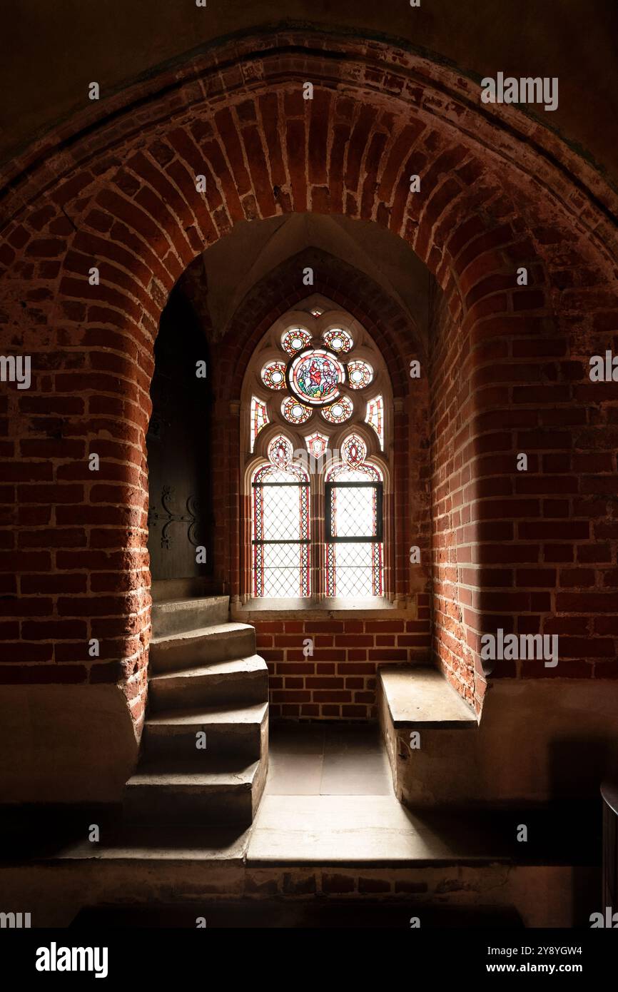 Diffused light from backlit ornate window illuminate spiral stairs at ...