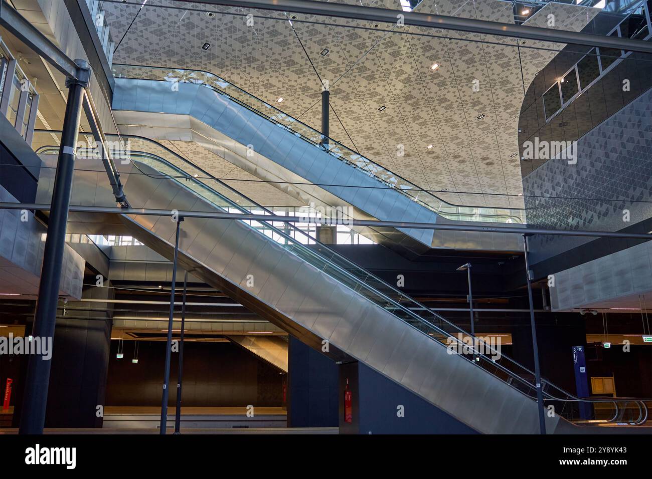 Modern train station platform with escalators and empty railway tracks ...