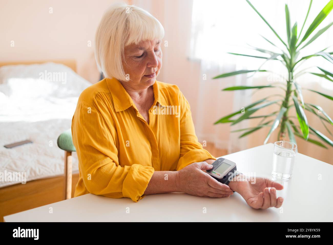 Senior woman with hypertension measuring blood pressure herself at home ...