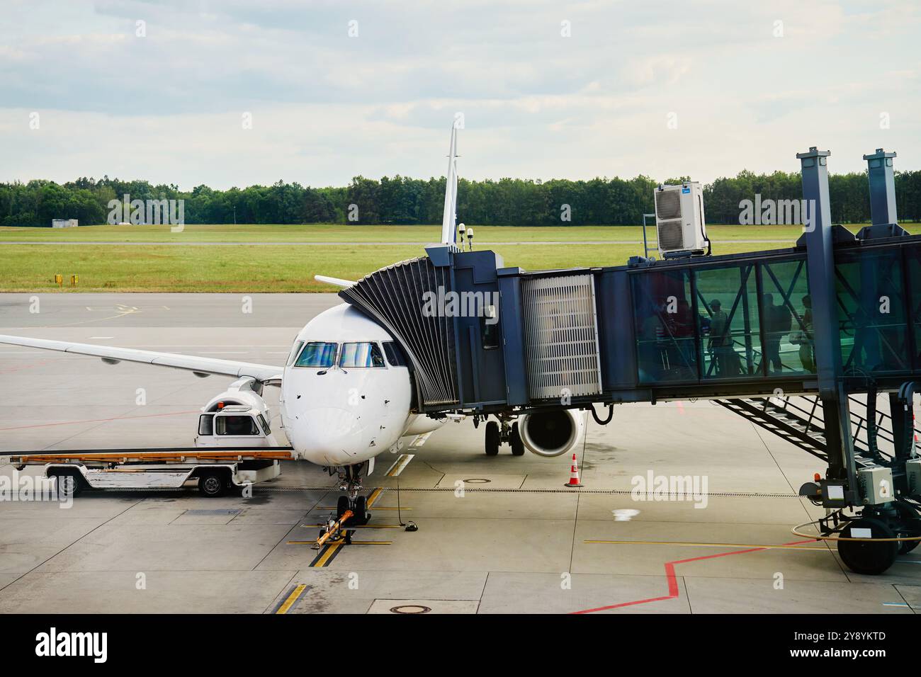 Passenger airplane docked at airport gate with connected jet bridge and ...