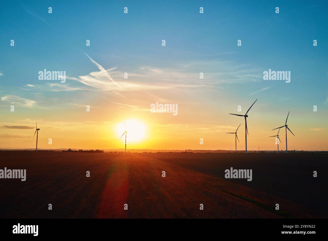 Silhouetted wind turbines in countryside landscape during sunset. Wind ...