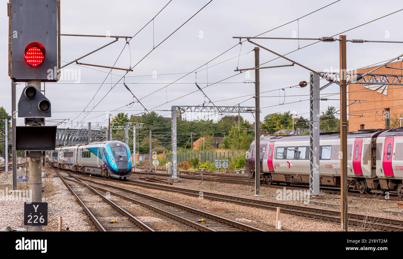 A train leaves a station as another approaches. A traffic signal is in ...