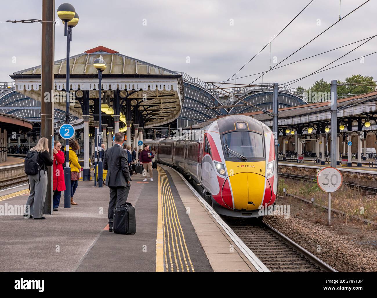 View of a railway station with passengers waiting as a train approaches ...