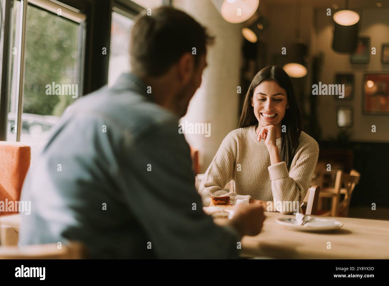 A couple enjoys a delightful moment in a warm café, sharing laughter ...