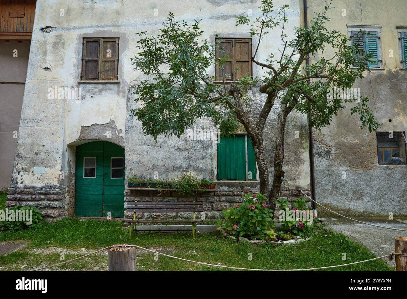 An old house in need of repair with garden and tree, in the village of ...