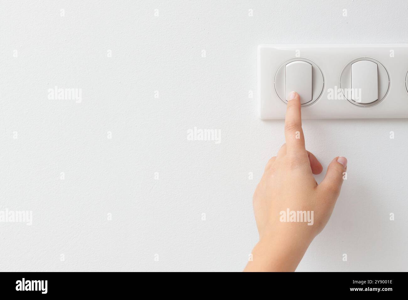 Female hand pressing light switch on or off to save energy at home ...