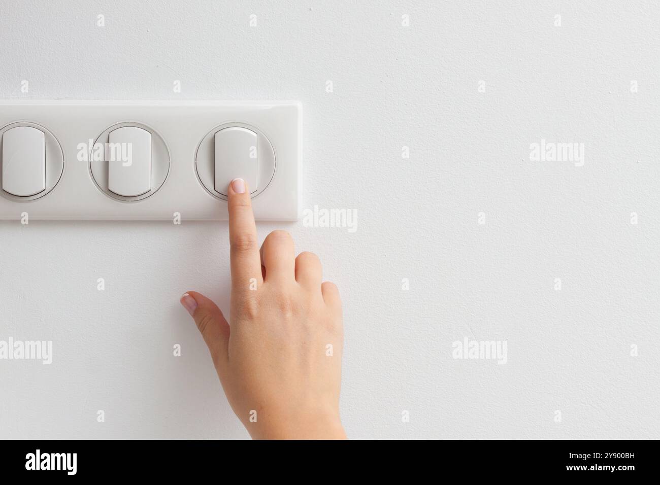 Female hand pressing light switch on or off to save energy at home ...
