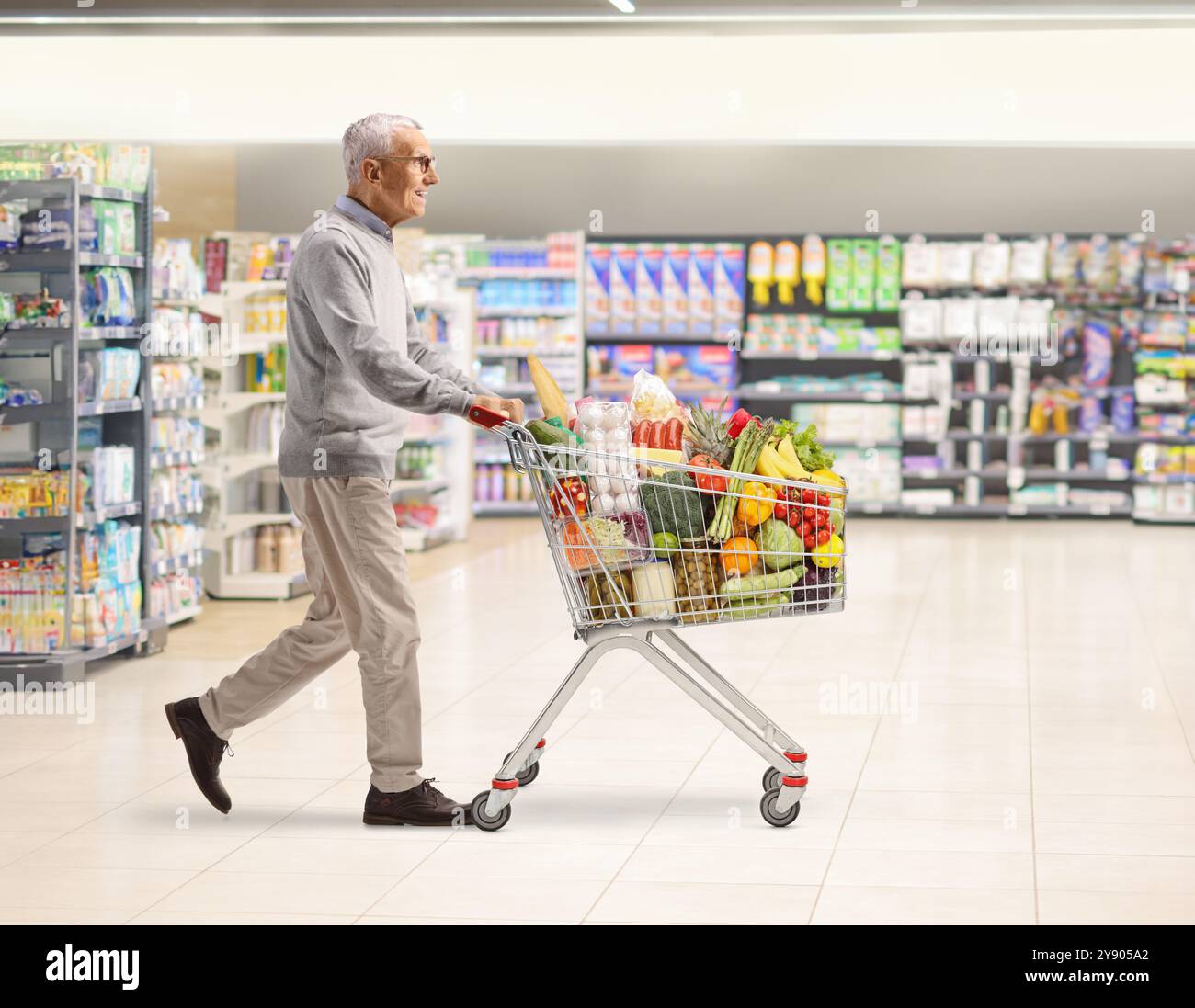 Mature male customer walking and pushing a shopping cart at a ...