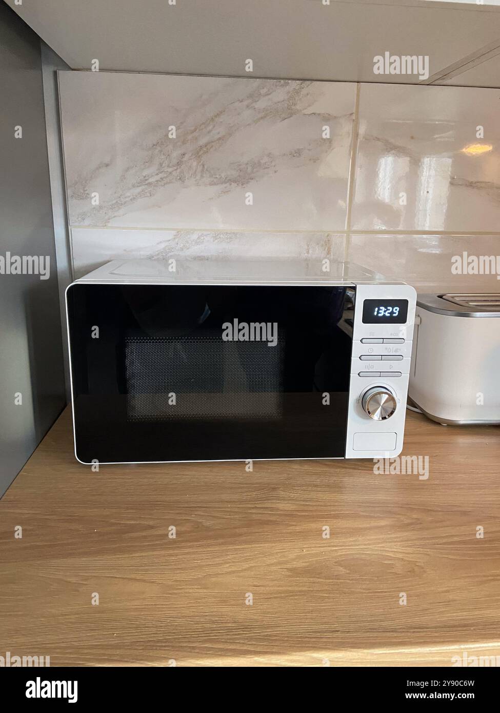 Modern kitchen corner features a microwave, a toaster on a wood ...