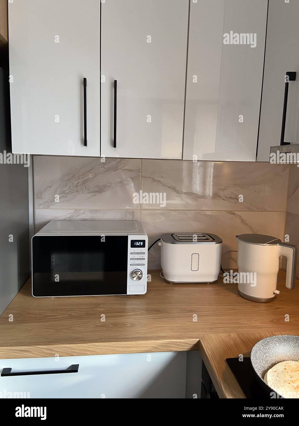 Modern kitchen corner features a microwave, a toaster, and an electric ...