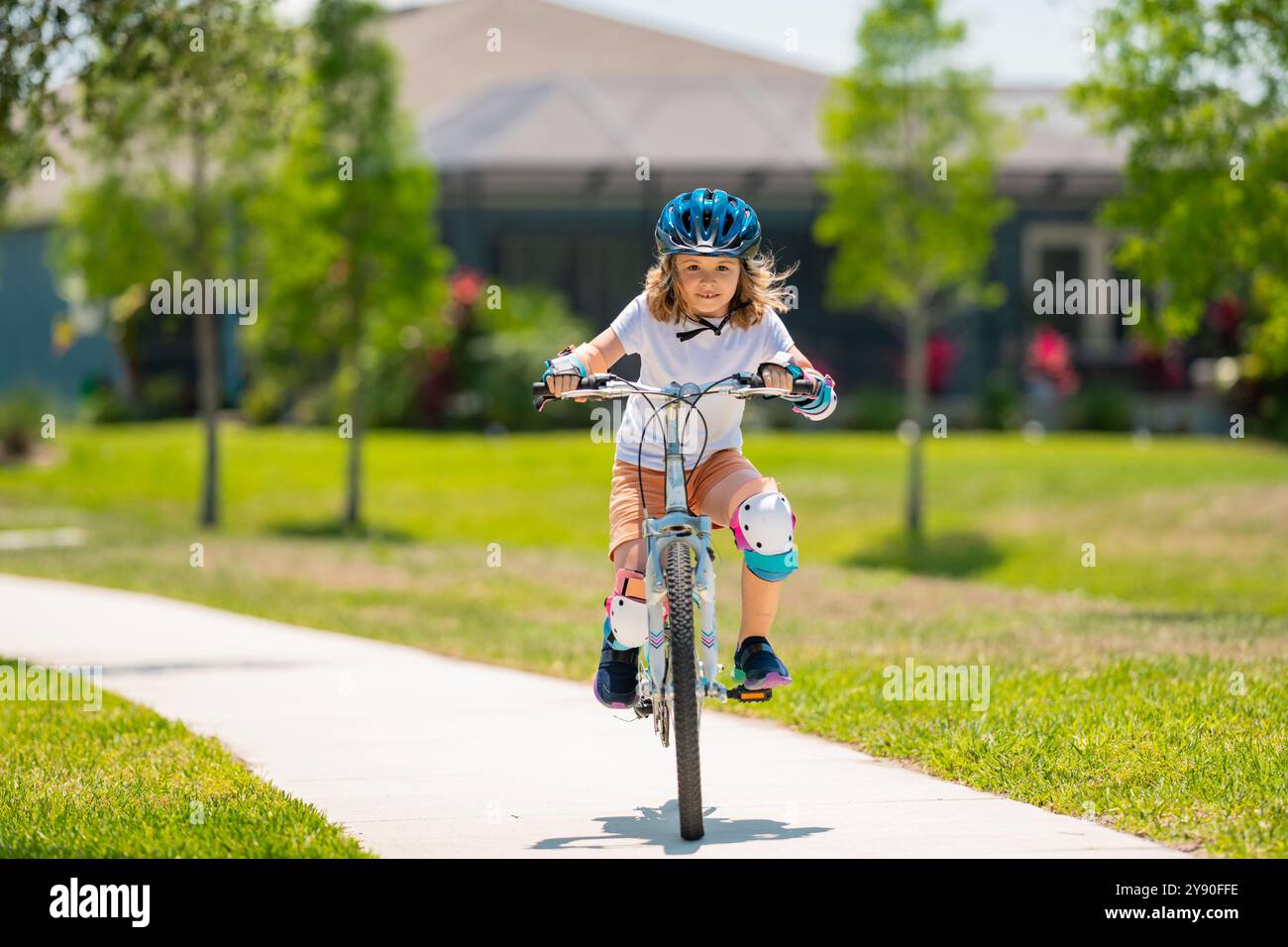 Child riding bicycle. Little kid boy in helmet on bicycle along bikeway ...