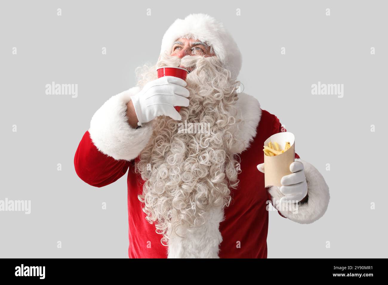 Santa Claus with cup of cola and tasty french fries on white background ...