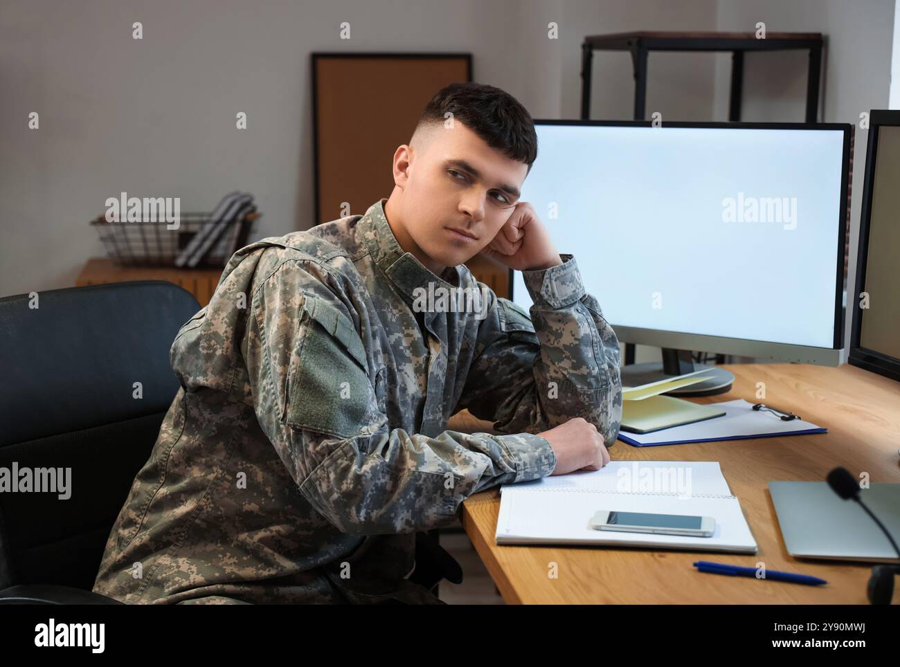Tired young male soldier sitting at table in headquarters Stock Photo ...
