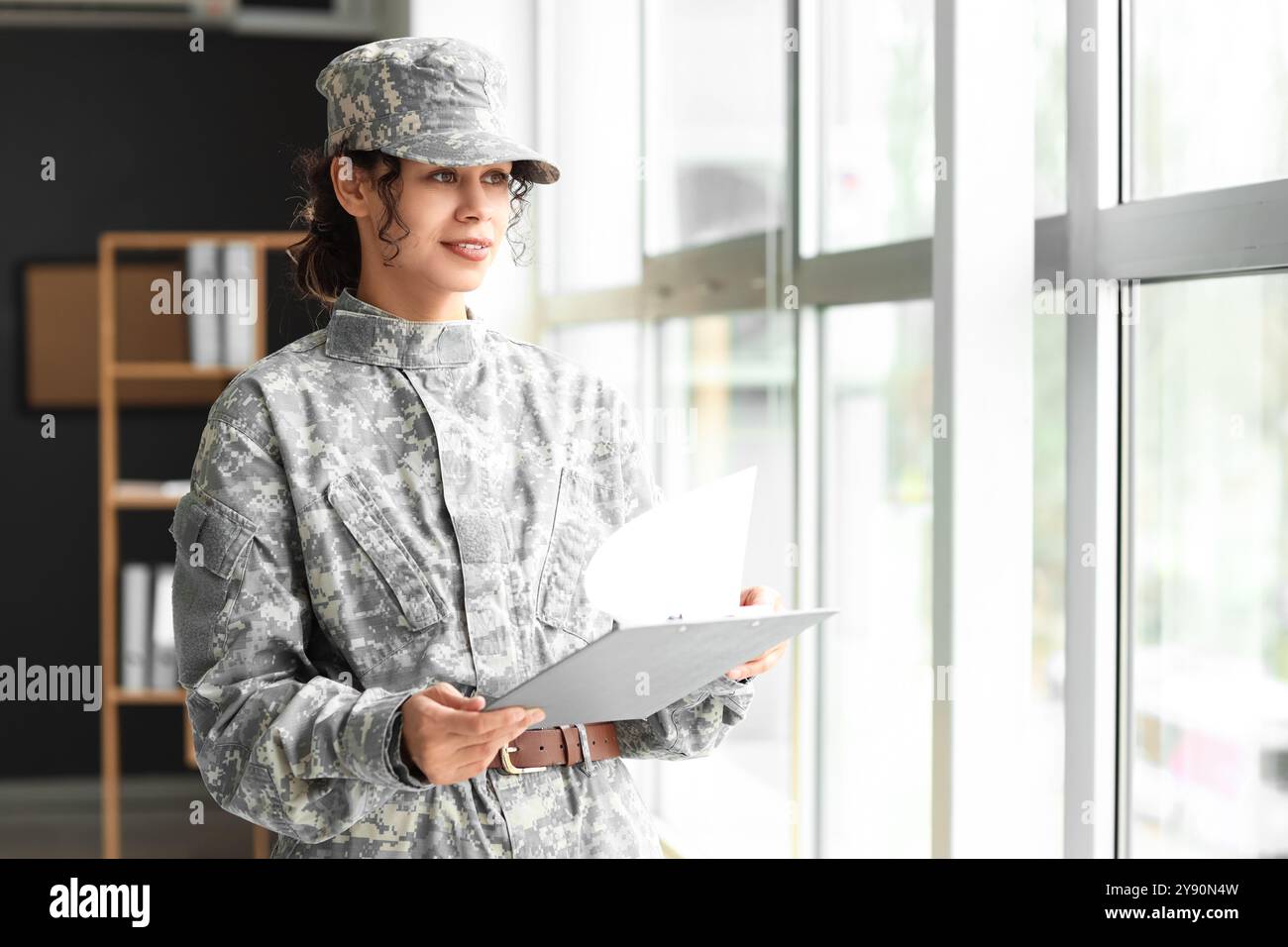 Female African-American soldier with clipboard near window at ...