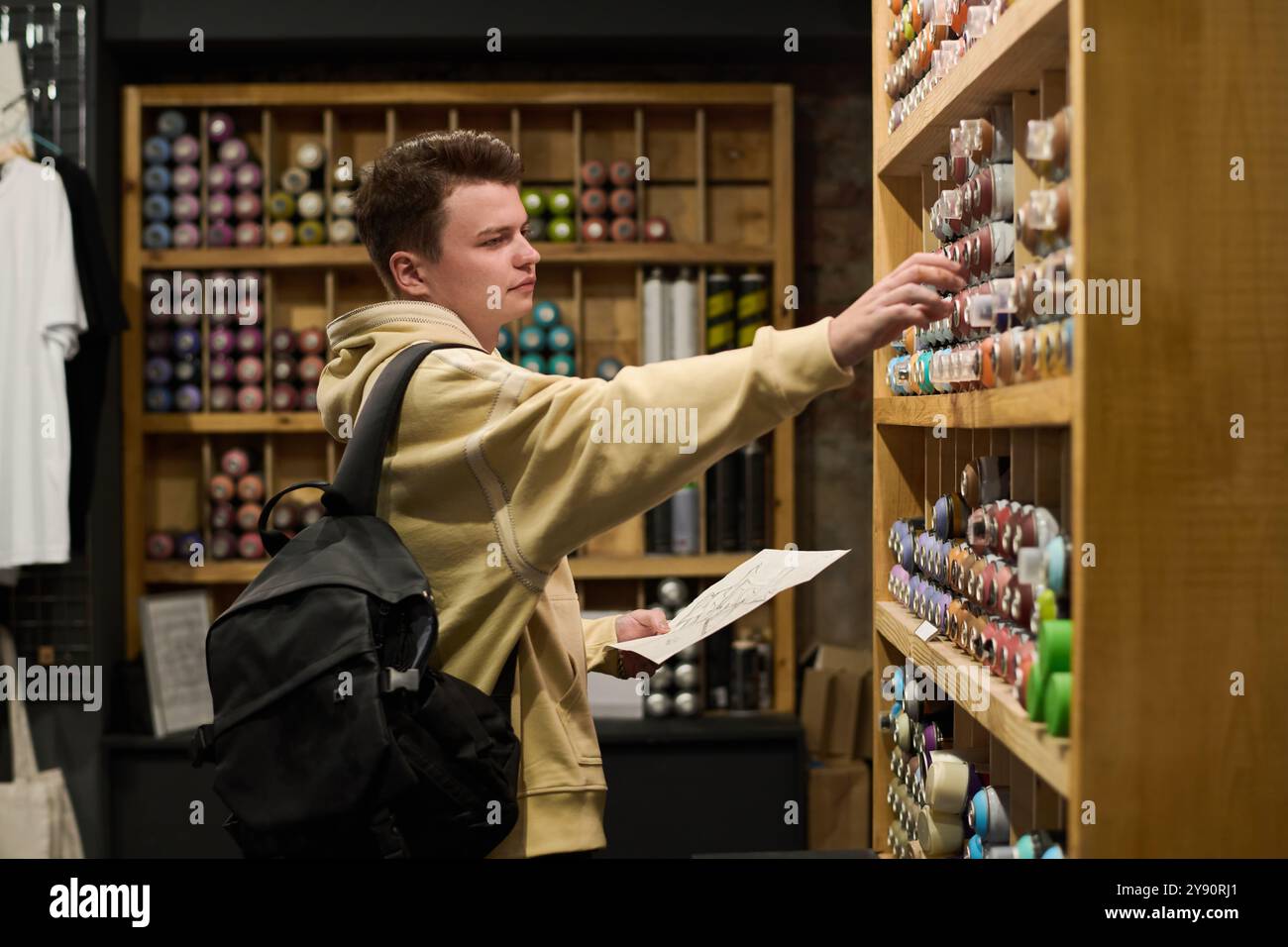 Side view of young man in beige hoodie standing in front of large ...