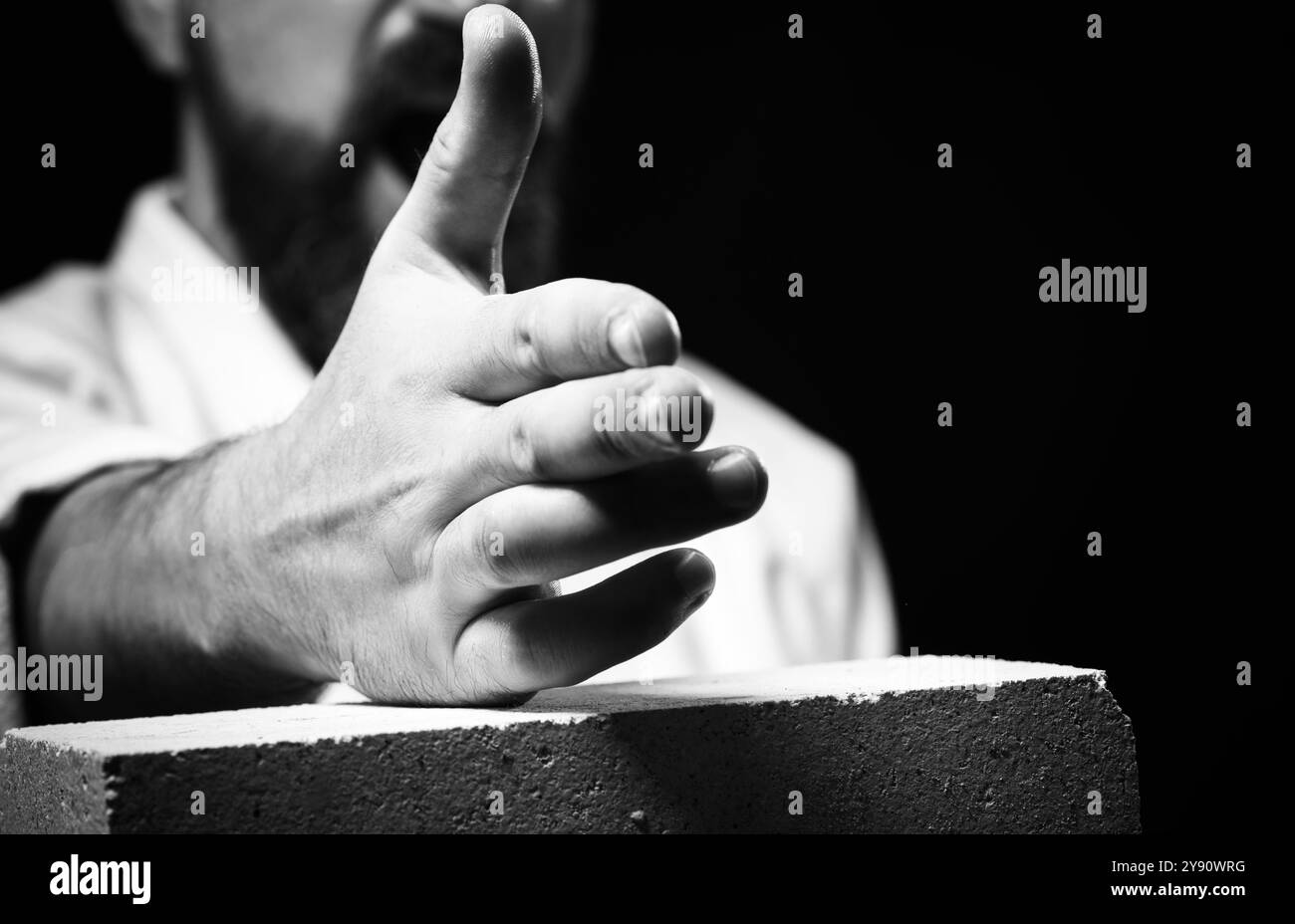Closeup of man's hand breaking concrete brick. Karate fighter smashes ...