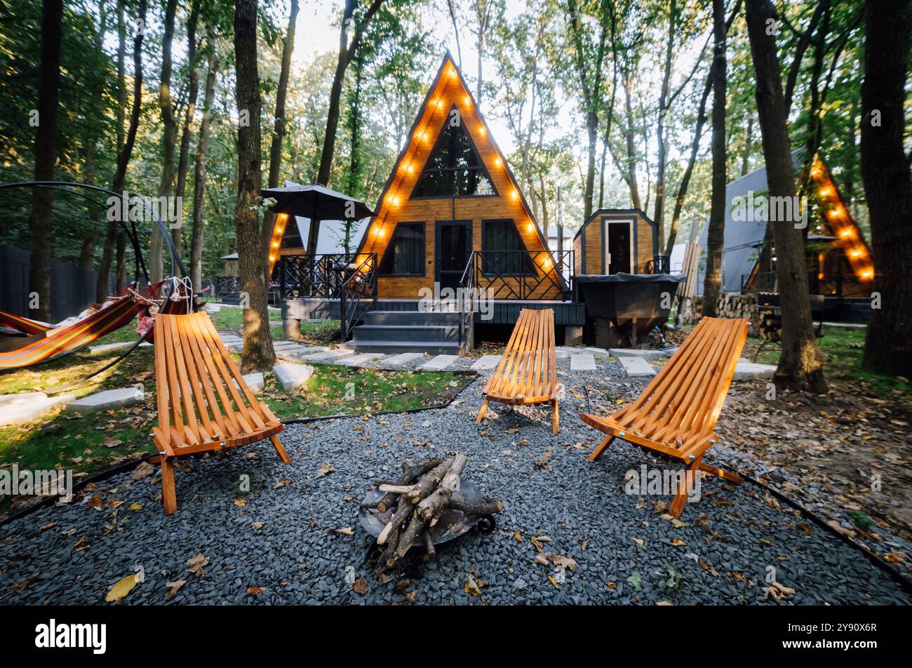 Modern A-frame cabin with illuminated exterior, surrounded by trees and ...