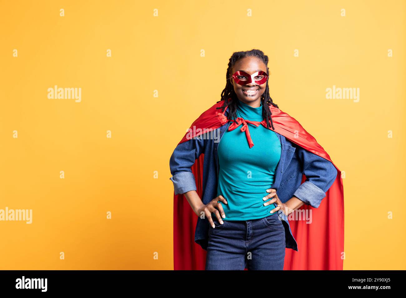 Happy girl portraying superhero with red cape, hiding identity and ...