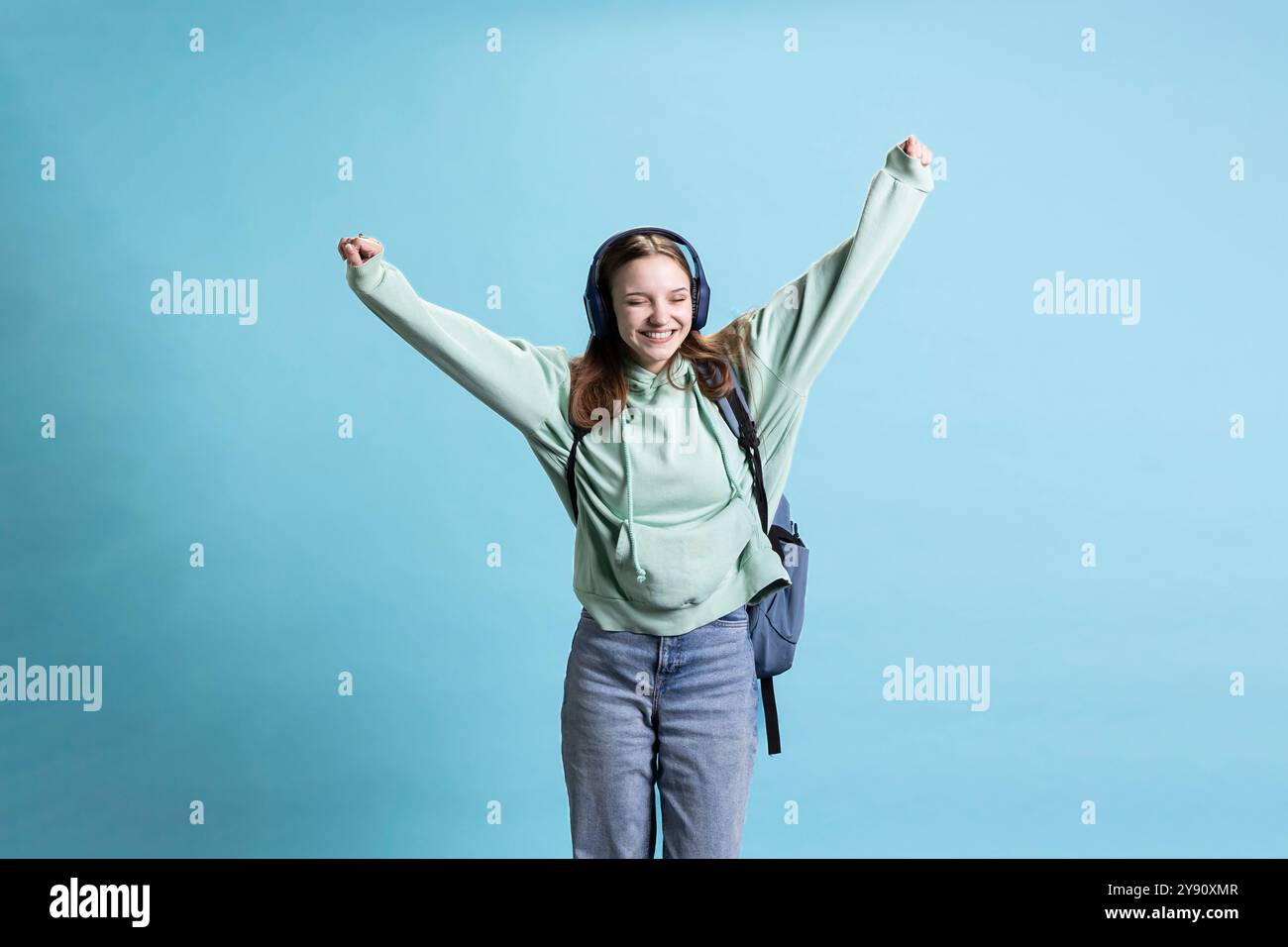 Woman raising hands in V shape, smiling, celebrating milestone, studio ...