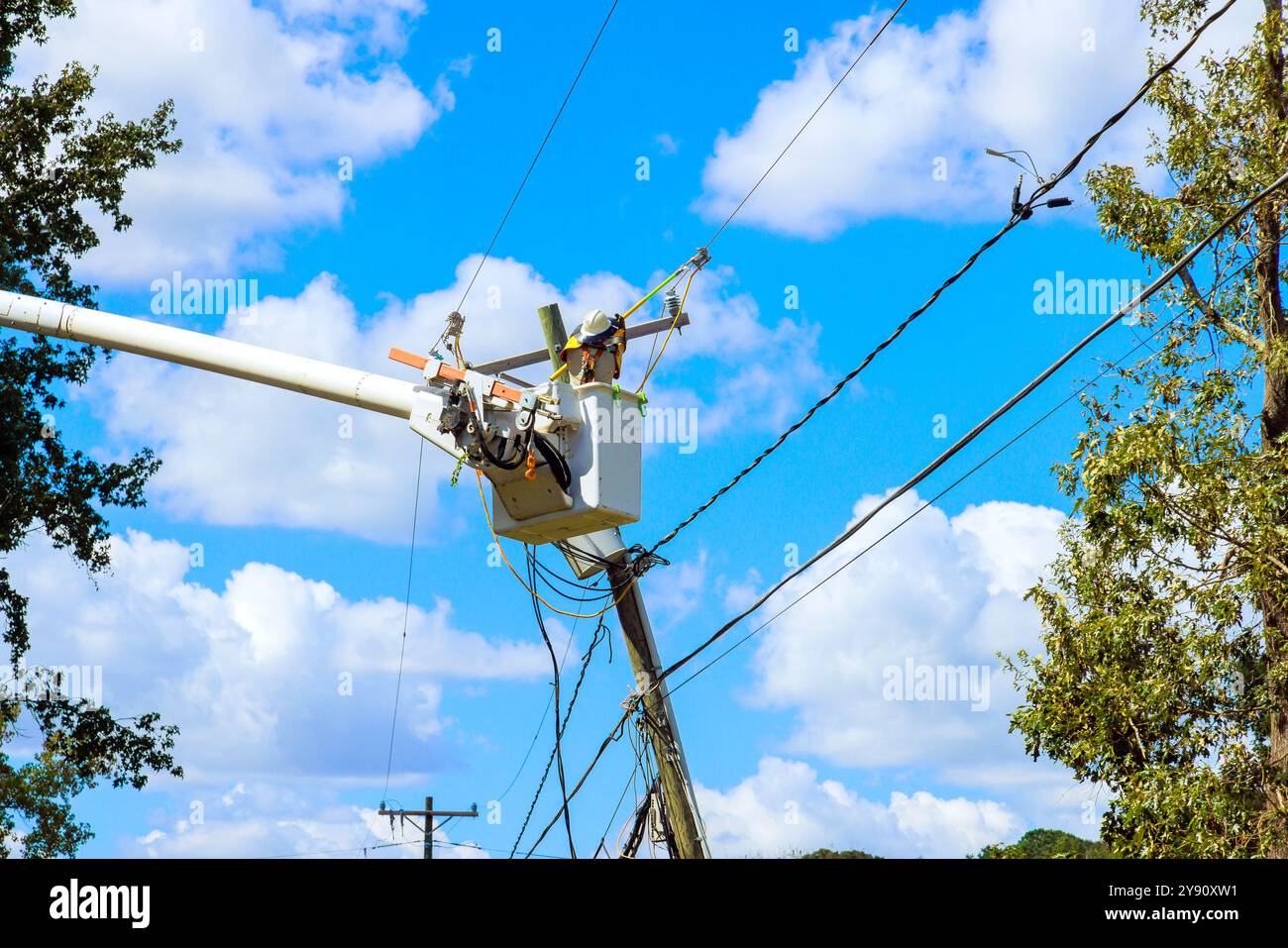 Using utility tower truck, emergency service linemen repair power ...