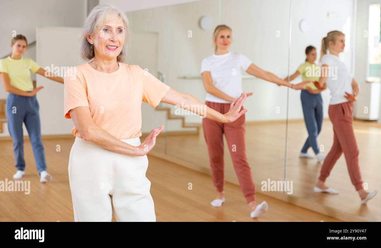 Positive woman doing aerobics exercises with group of people in dance ...