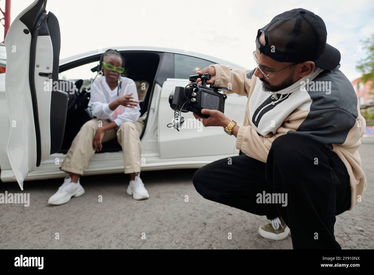 Man holding camera recording woman sitting in car while adjusting ...