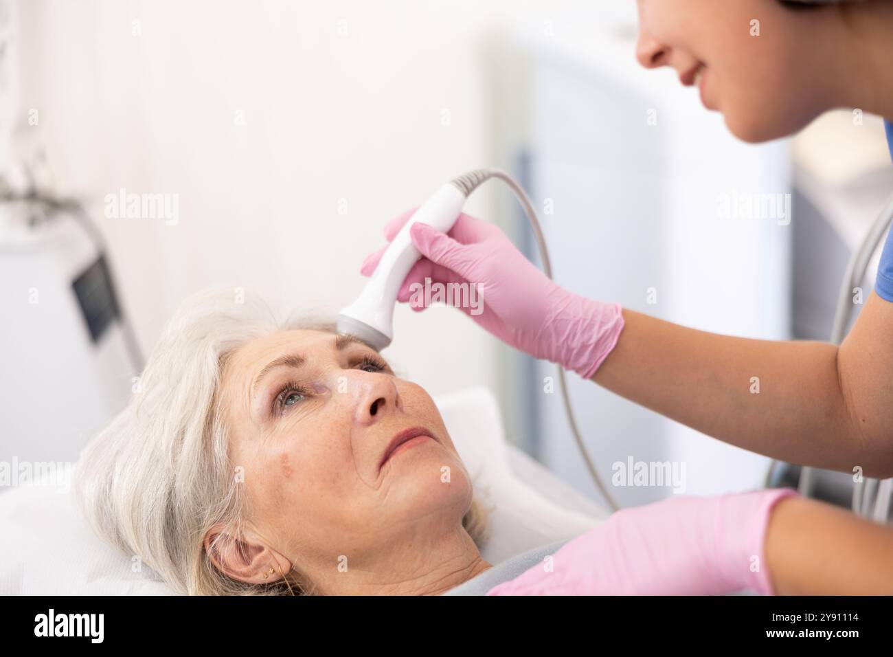 Mature female visitor receiving hardware electric lifting massage with ...