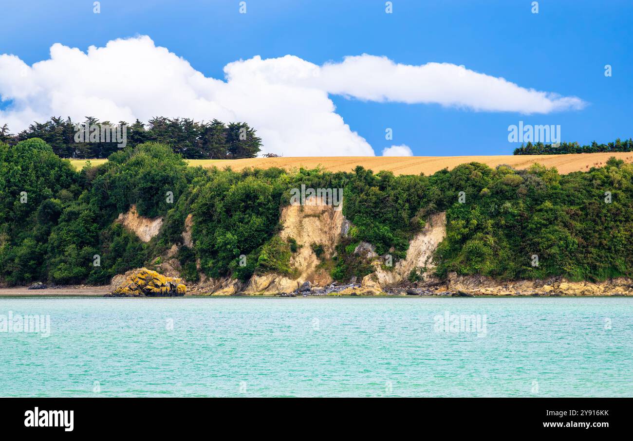 A serene coastal landscape in Brittany featuring a calm turquoise sea ...