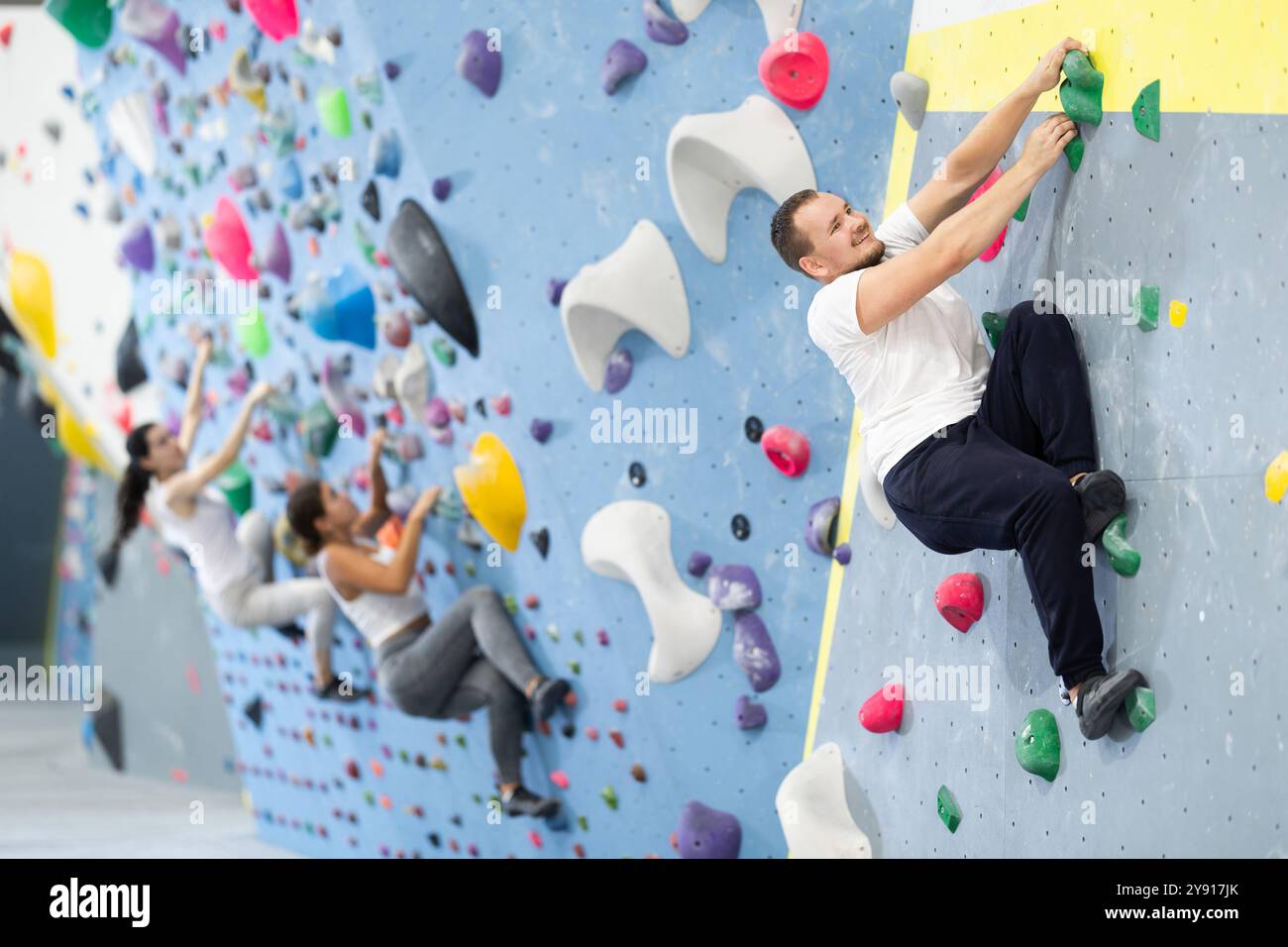 Man climbing a tall, indoor, man made rock climbing wall Stock Photo ...