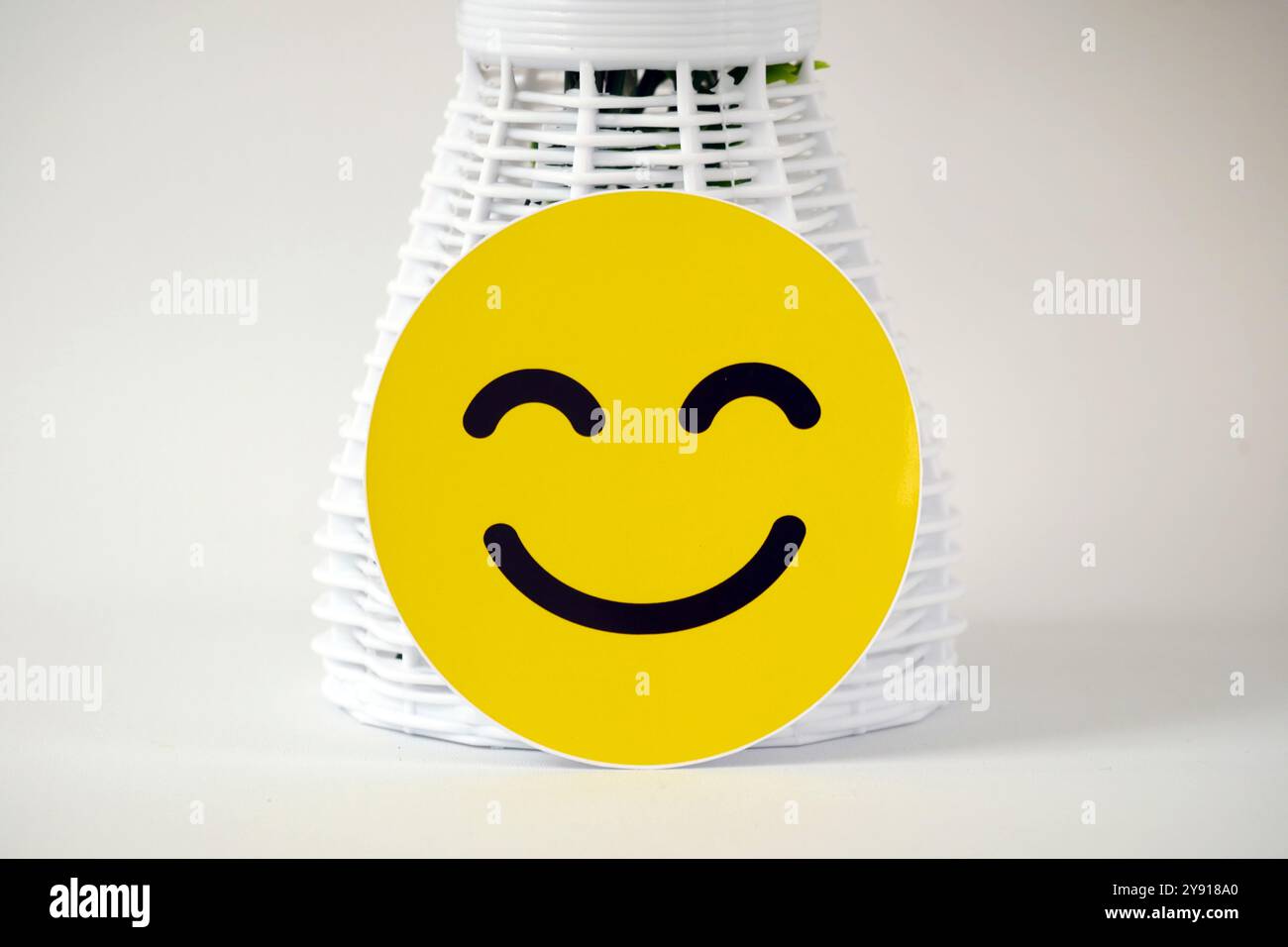 Yellow smiling emoticon card leaning on white flower vase Stock Photo ...