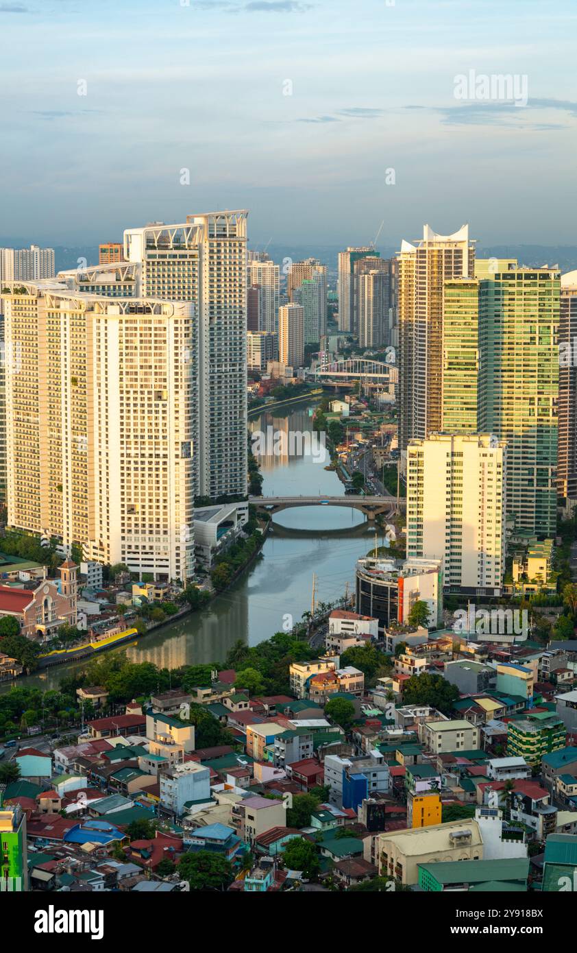 The Pasig River,with high,tall modern buildings lining the riverbanks ...