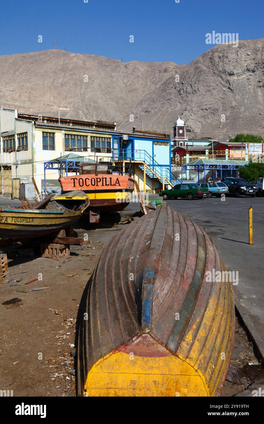 Wooden fishing boats on quay of port, Coya Sur clock tower in ...