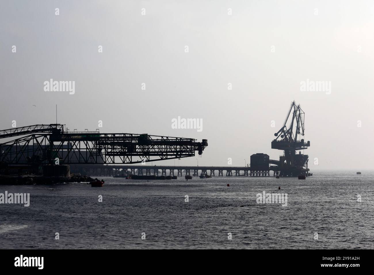 Jetties and gantry cranes for loading minerals onto ships in port ...