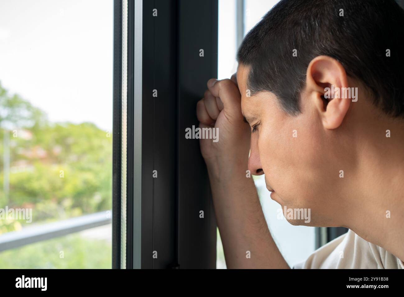 Side view portrait of a sad single man and mad by the window in regret ...