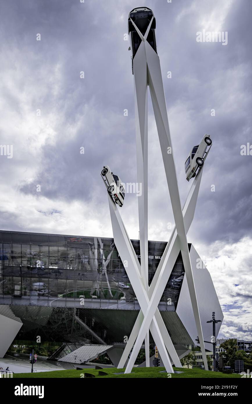 Modern sculpture of cars on high pillars in front of a modern building ...
