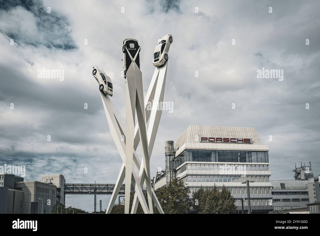 Modern sculpture of cars on high pillars in front of a modern building ...