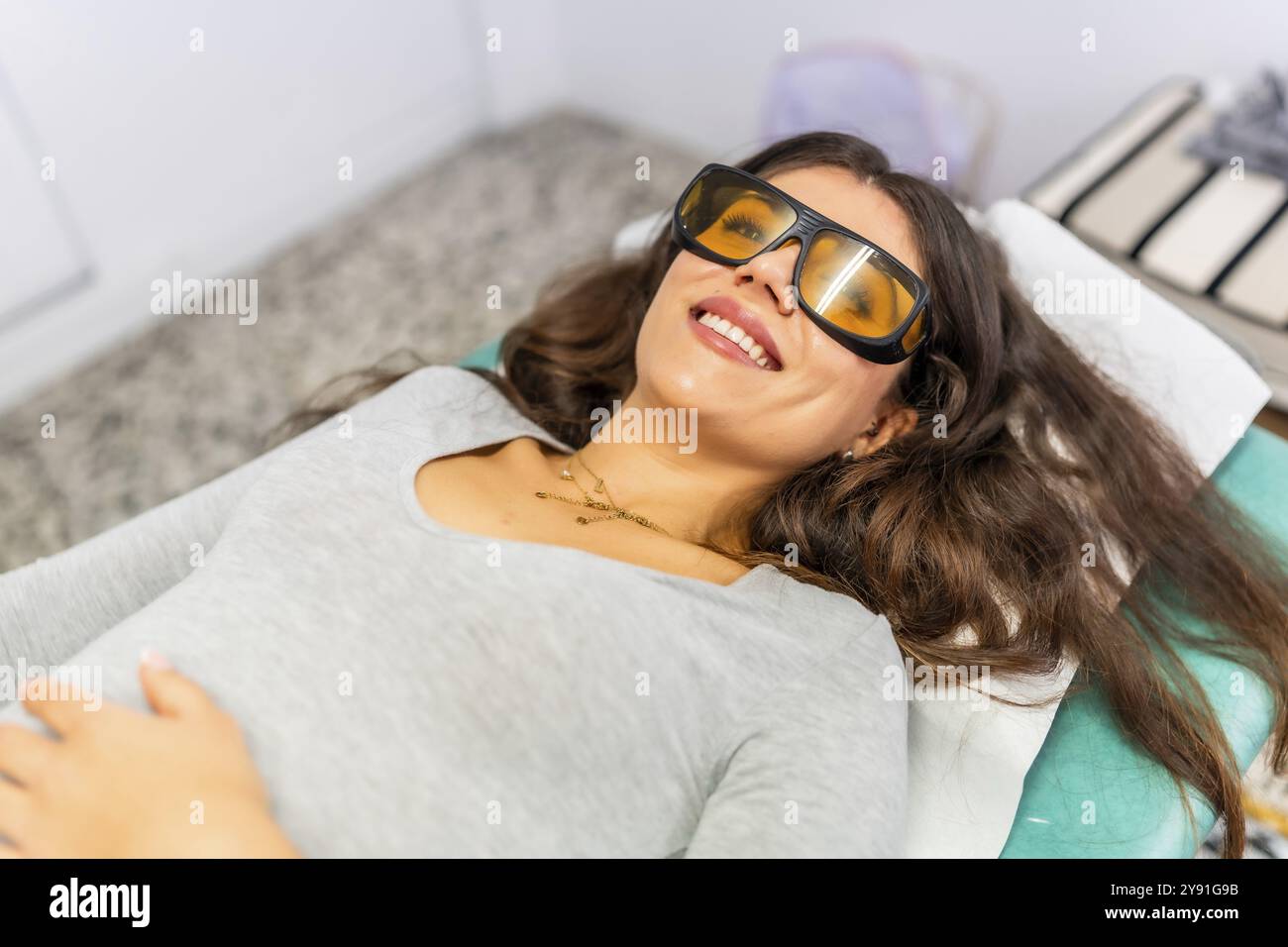 Smiling caucasian woman lying on stretcher with safety goggles ready ...
