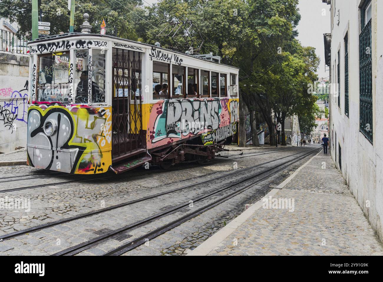 Tram sprayed with graffiti, travelling down a steep, narrow, path ...