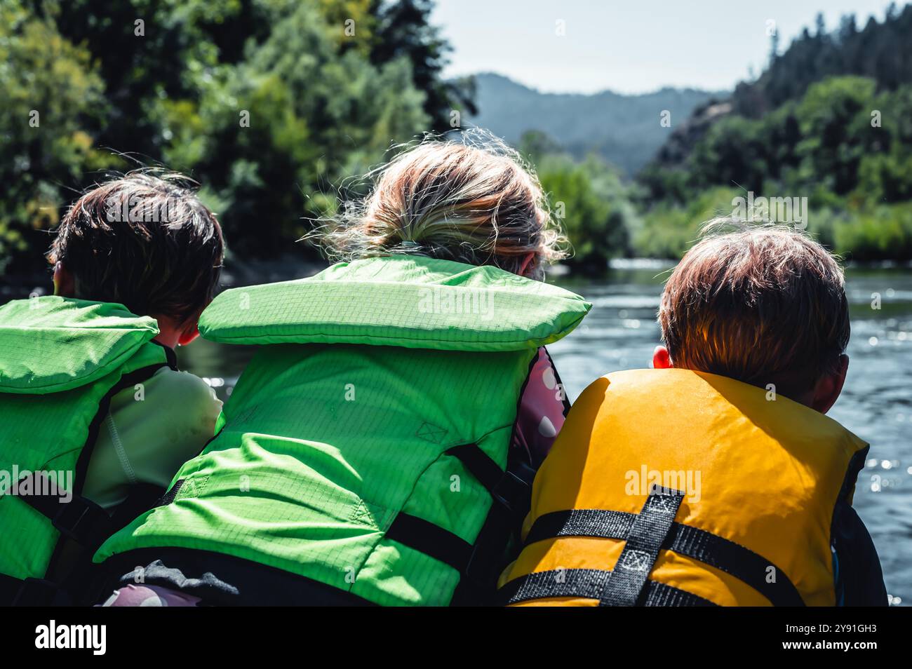Selective focus on three children peering over a raft going down the ...