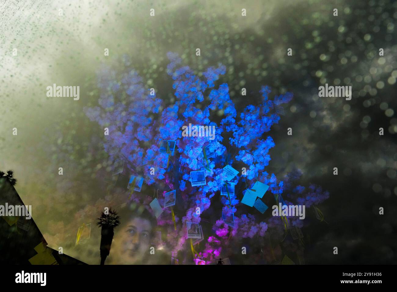 Jewish community members look at a tree decorated with photos of ...