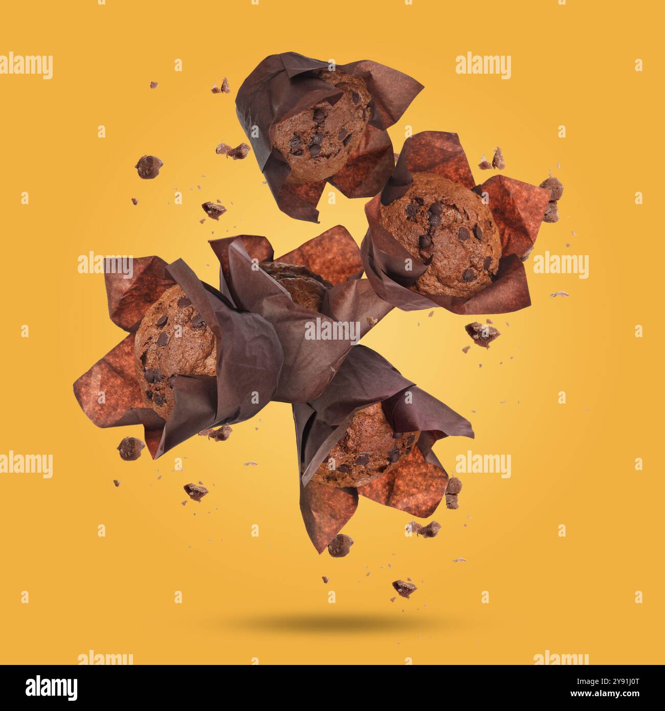 Delicious chocolate muffins and crumbs falling on golden background ...