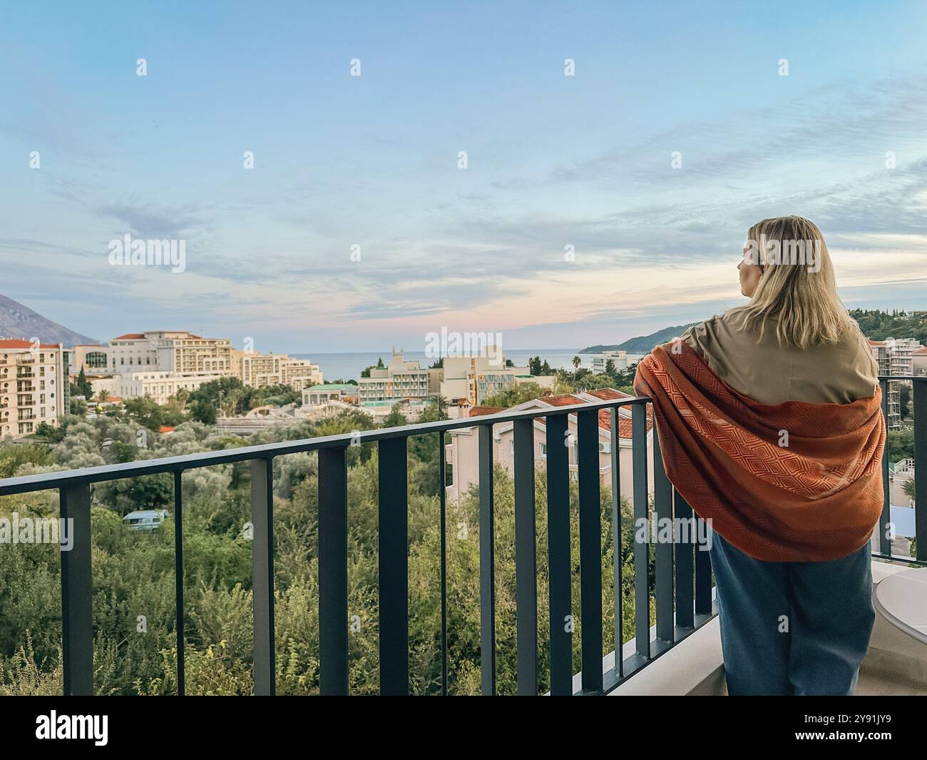 A woman standing on the balcony at summer sunset in Montenegro Stock ...