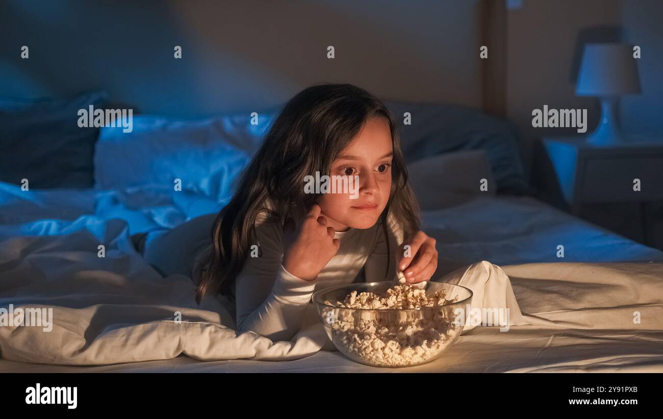 Night movie. Child home leisure. Curious little girl enjoying watching ...