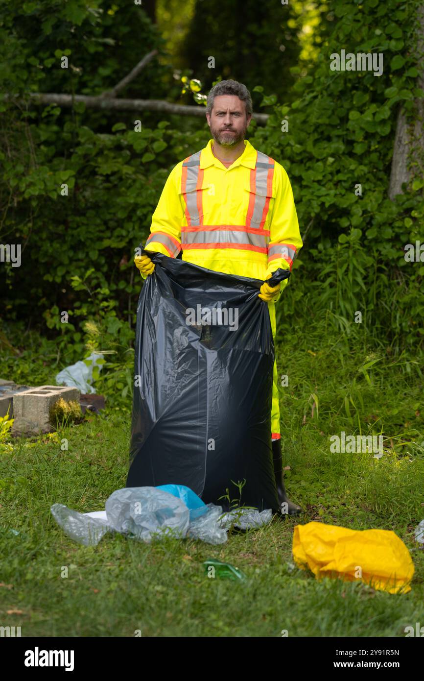 Environment plastic pollution. Volunteer collecting trash in the forest and holding a garbage ...