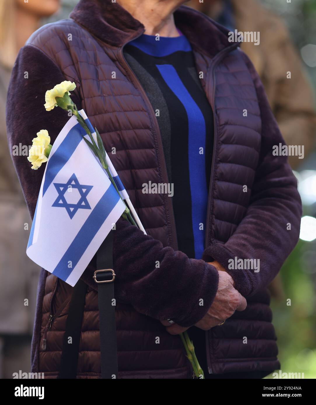 Details with the hands of a woman holding the Israeli flag and a flower ...