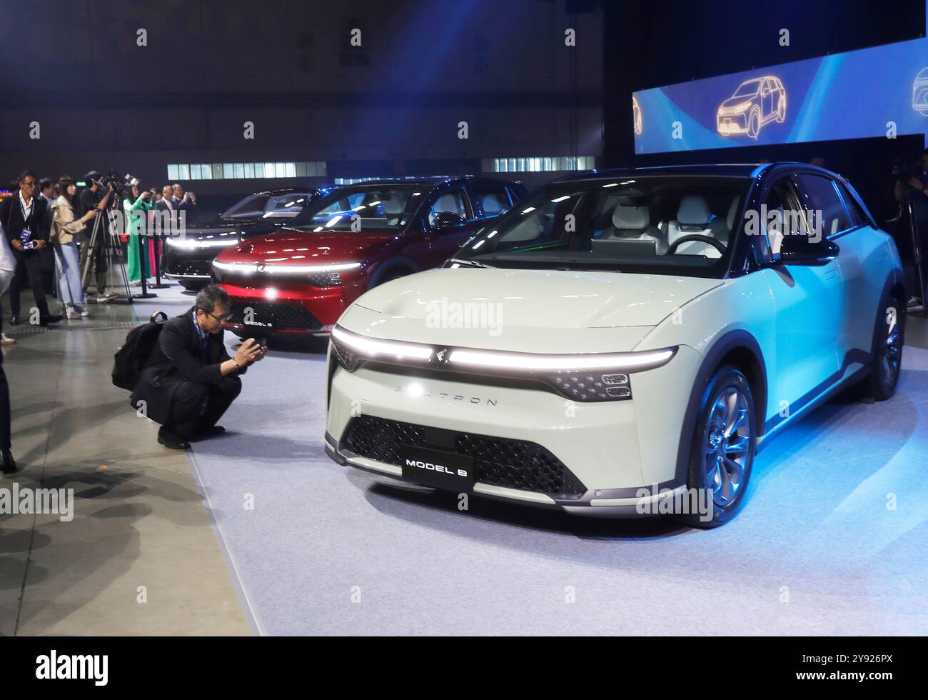 Visitors look at a series of Foxtron electric cars during the Hon Hai ...