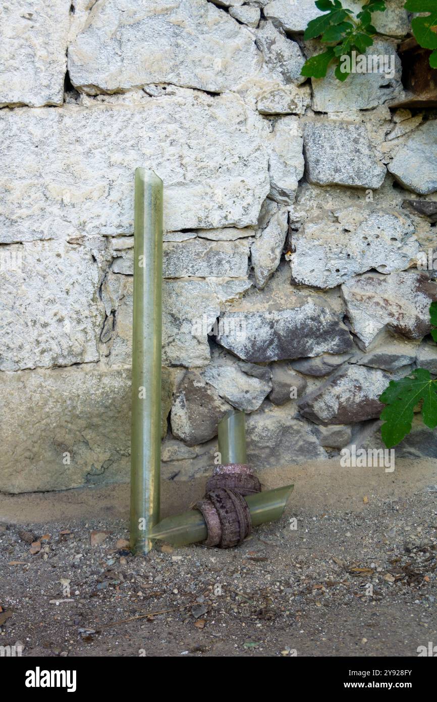 Greenish glass pipe with rusty coupling near grey stone wall Stock ...