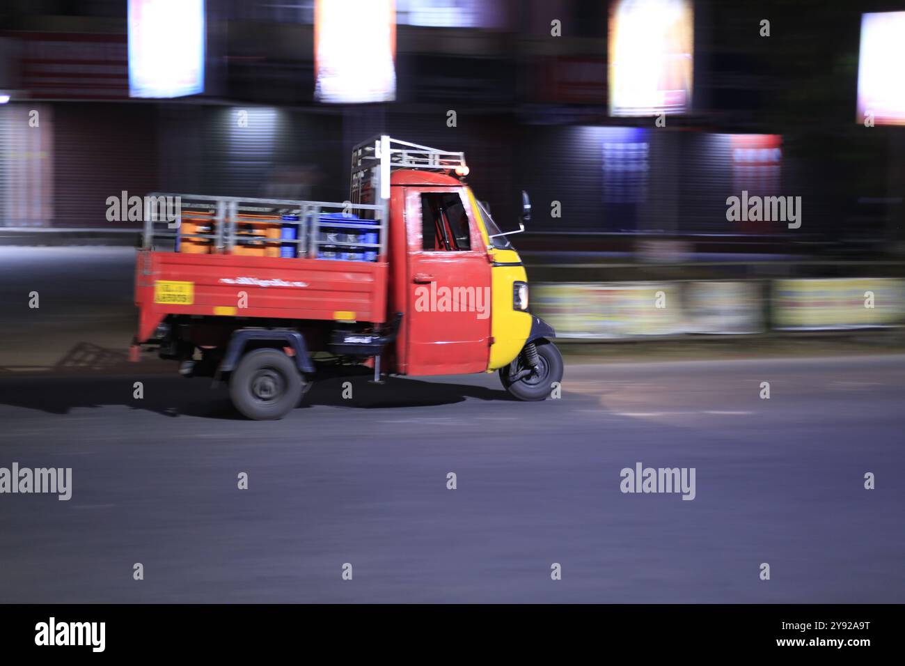 A delivery auto-rickshaw carrying crates on a quiet night street ...