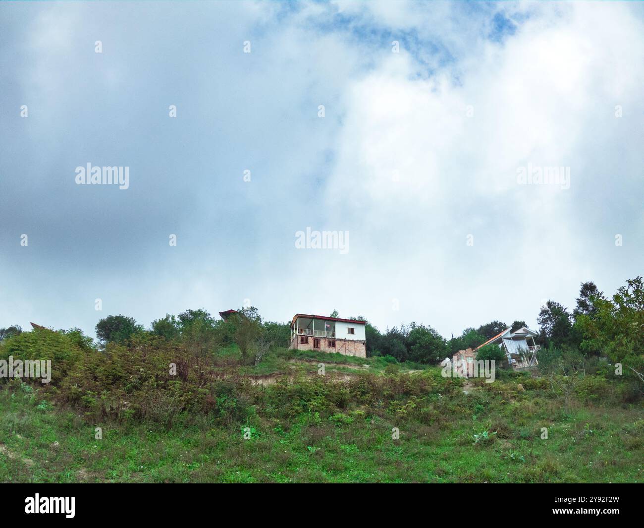 Small hillside houses under a cloudy sky, surrounded by green nature ...